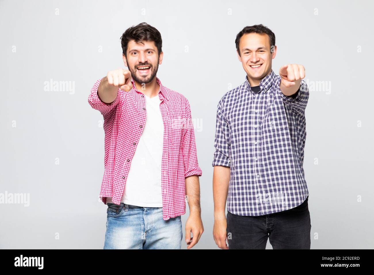 Two men over isolated background points finger at you while smiling ...