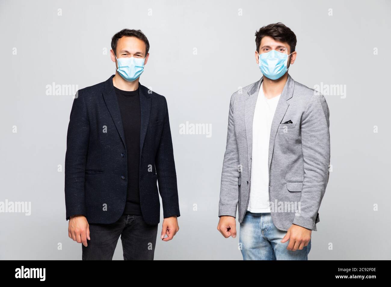 Two young man in medical mask in suits at a meeting on a white ...