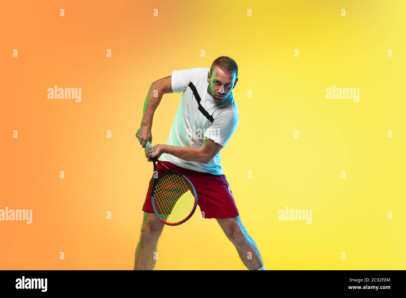One caucasian man playing tennis isolated on studio background in neon ...