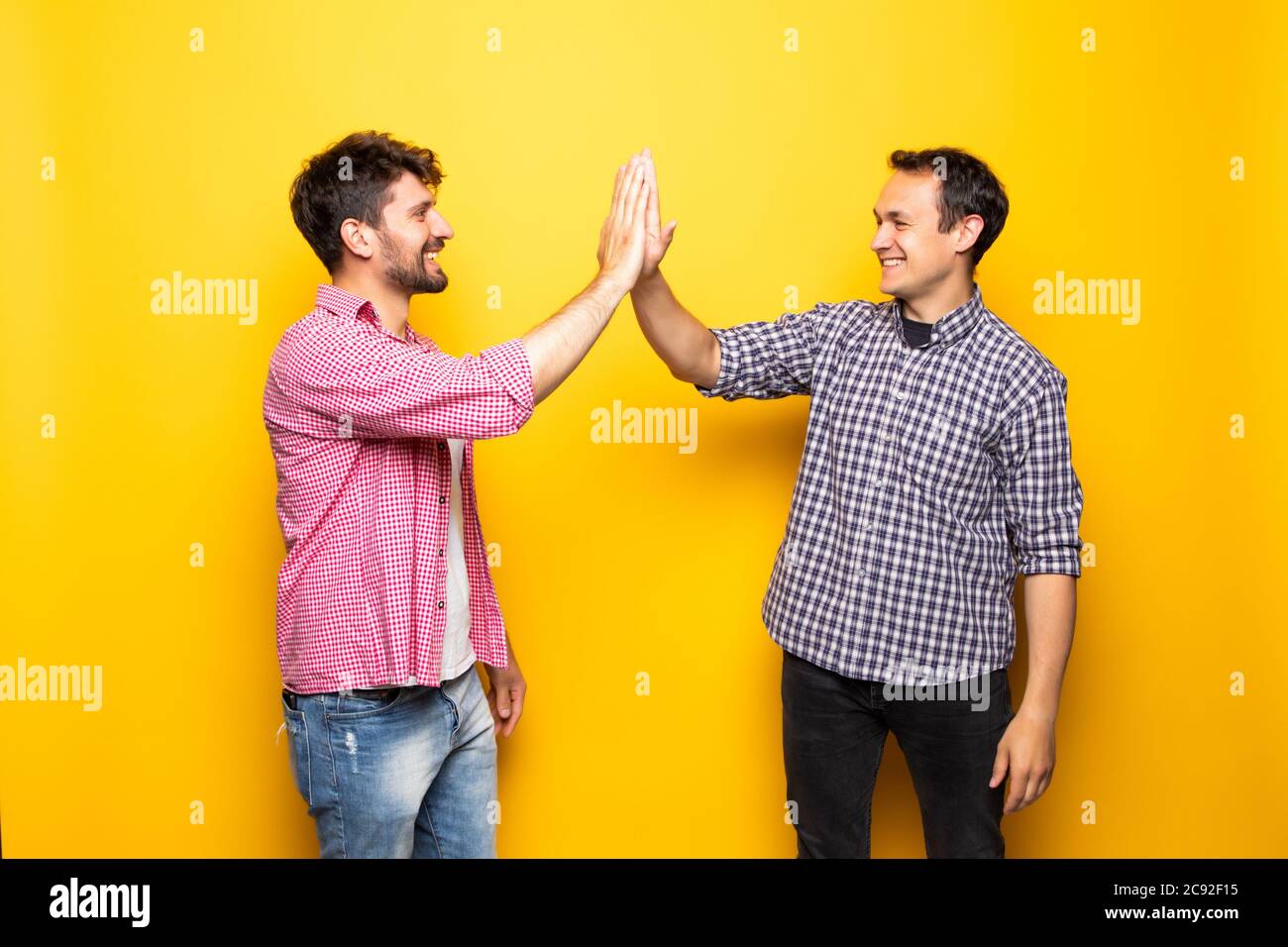 Portrait of a two delighted young men celebrating with high five ...