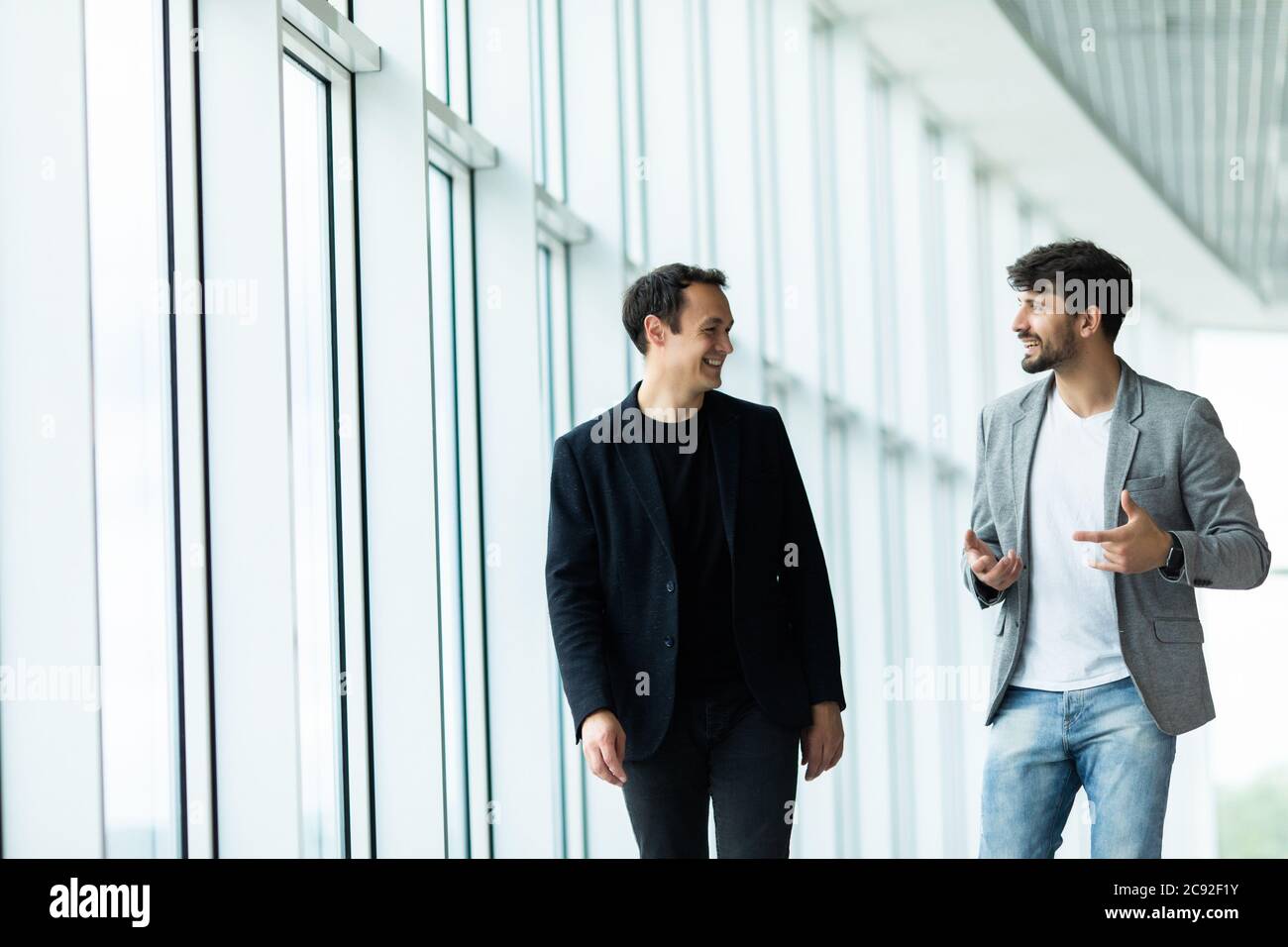 Two businessmen talking while walking through office corridor Stock ...