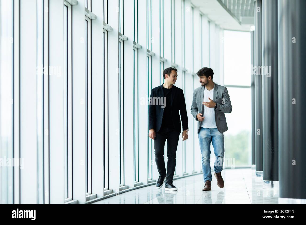 Two businessmen talking while walking through office corridor Stock ...