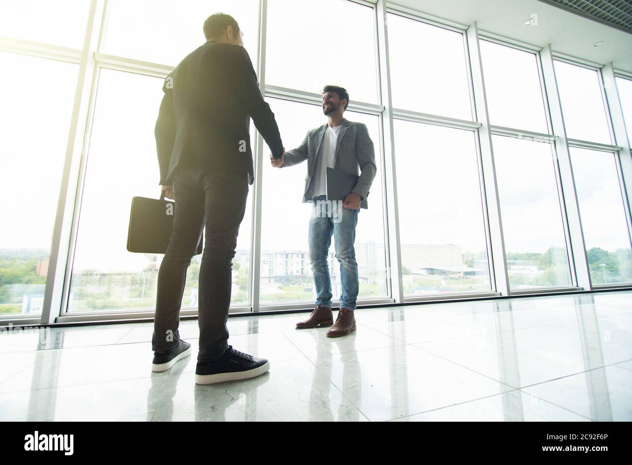 Two businessmen handshake in office with big panoramic windows Stock ...