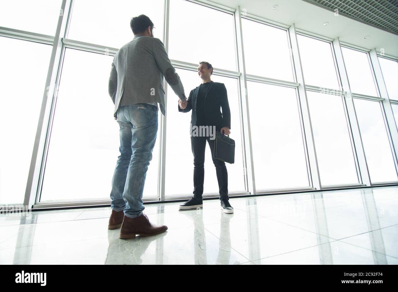 Two businessmen handshake in office with big panoramic windows Stock ...