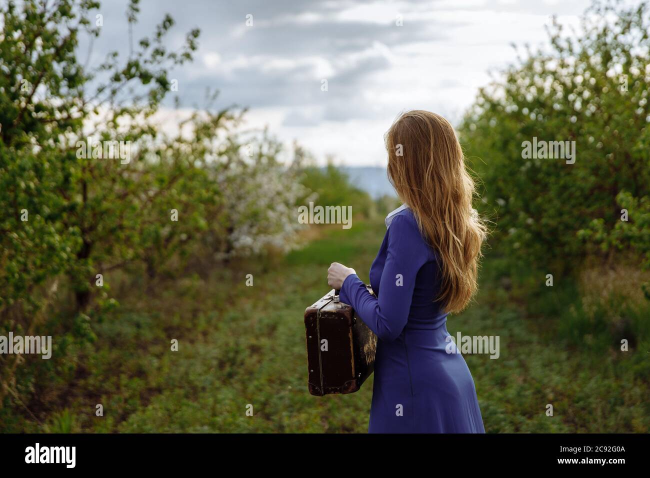 A blonde in a blue dress looks into the distance Stock Photo - Alamy