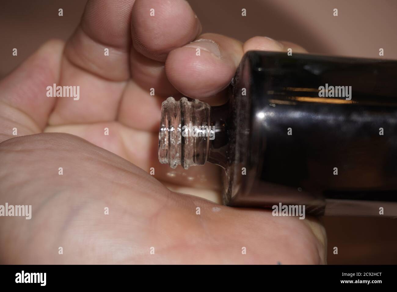Person trying to pour a liquid onto their hand from a black container ...