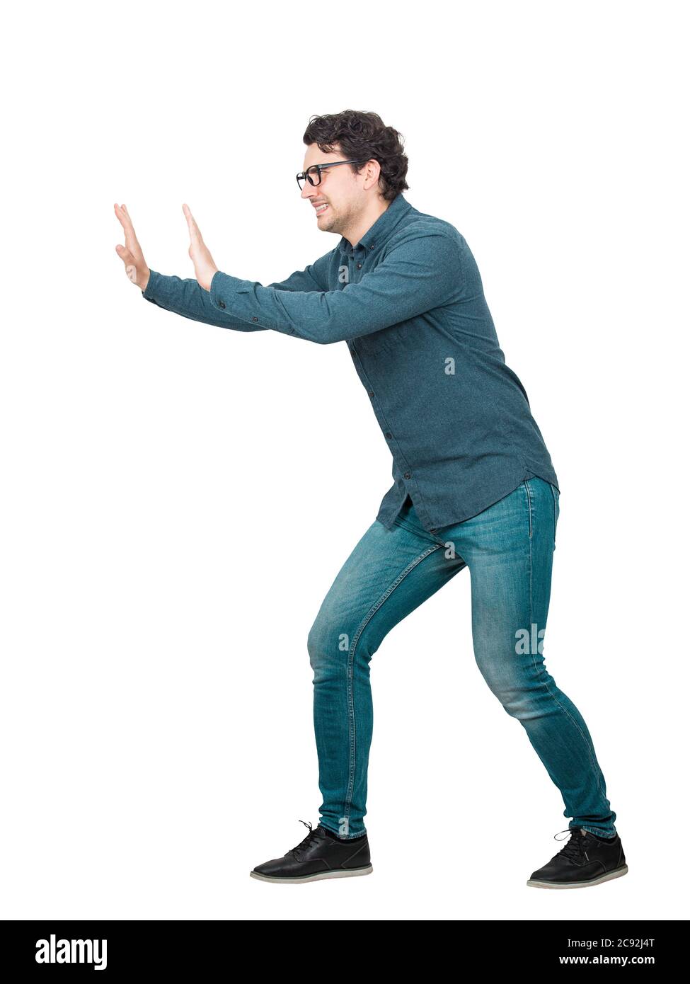 Determined businessman makes effort pushing an heavy invisible object ...