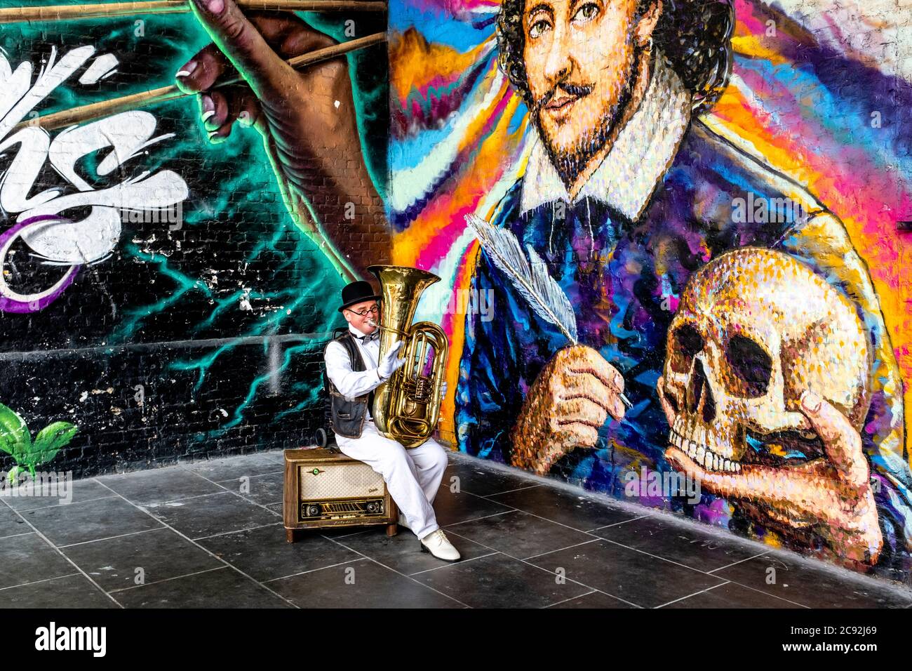 A Street Entertainer Plays Music In Front Of A Giant Mural Of William ...