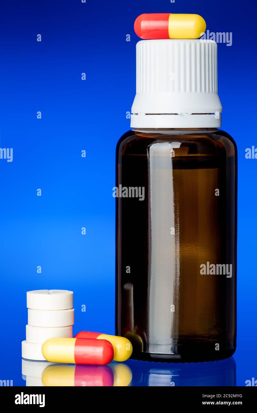 Cough syrup, glass bottle with a yellow-red pill and round tablets on ...
