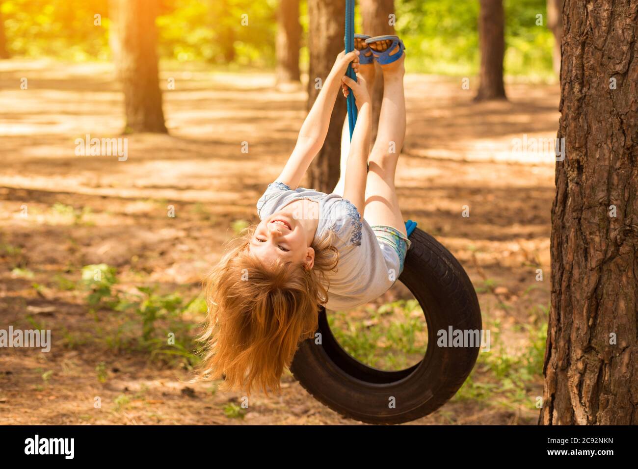 Happy active child girl playing on swing wheel in forest on sunny ...