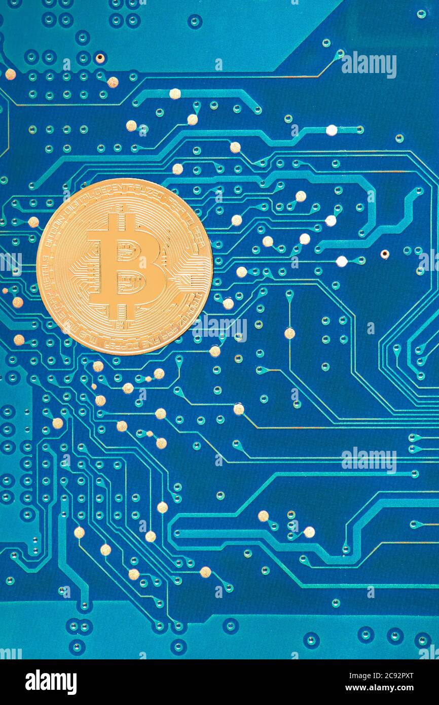 The bitcoin lies on the motherboard, the gold coin of the crypto currency on the blue printed ...
