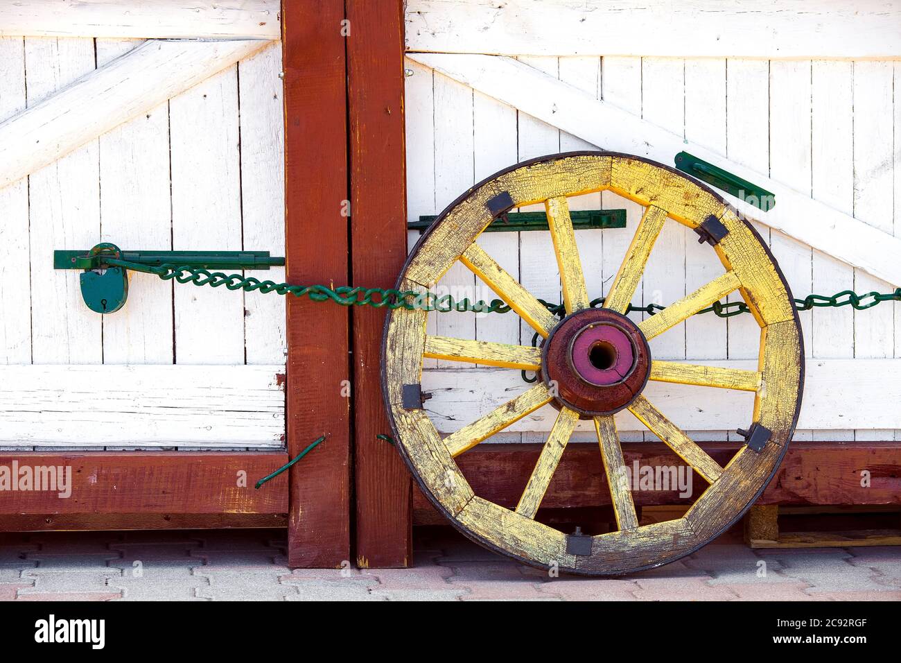 wheel of the wooden cart costs near wooden gate Stock Photo - Alamy