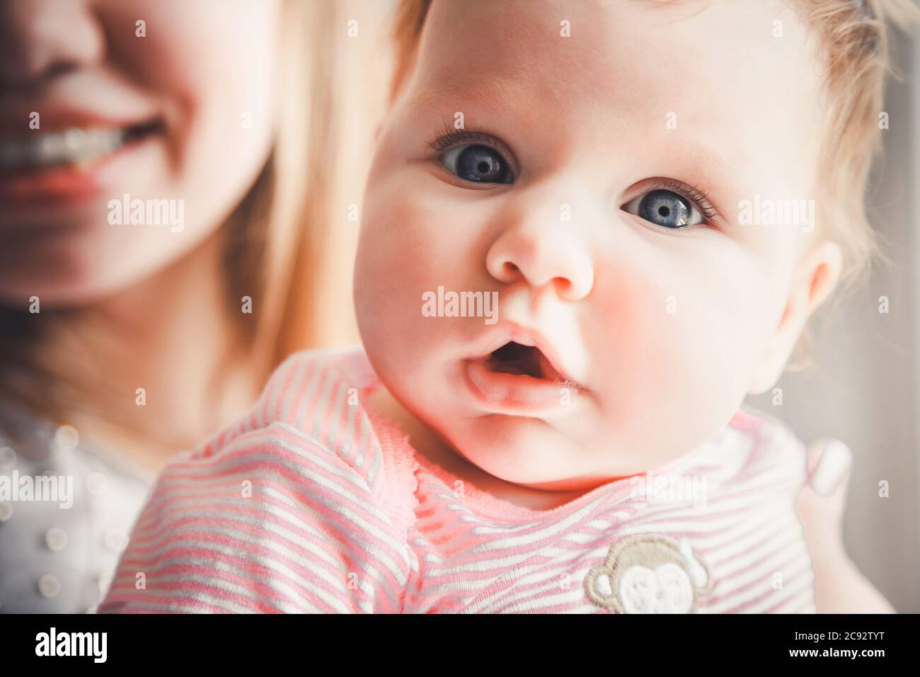 Close-up of newborn baby looking at camera in mother's hands. Family at ...
