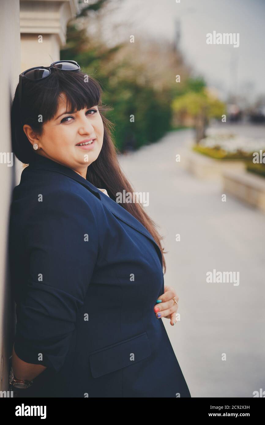 Happy smiling beautiful overweight young woman in dark blue jacket ...