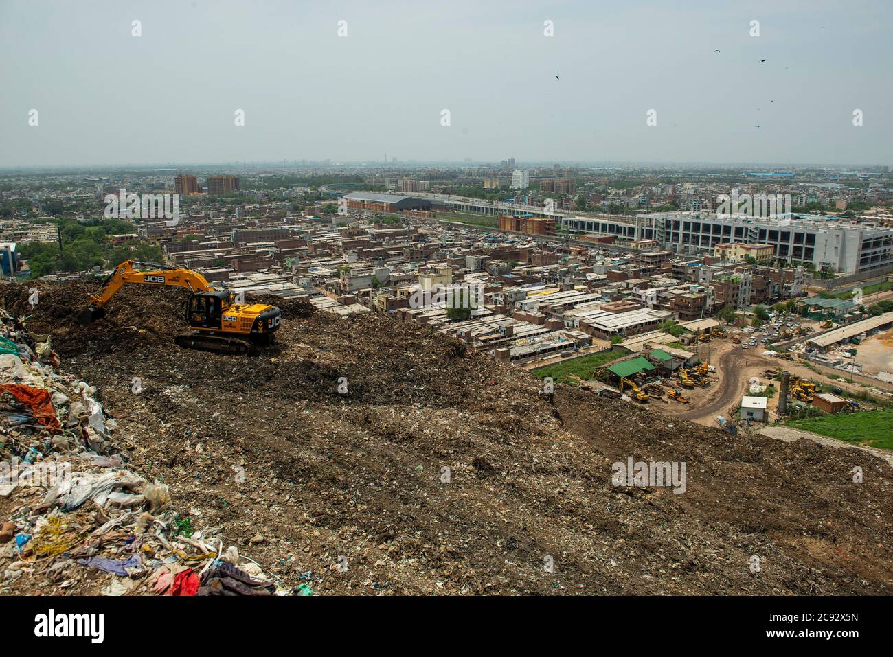 A JCB machine picking up waste in the pile of garbage.Waste segregation ...