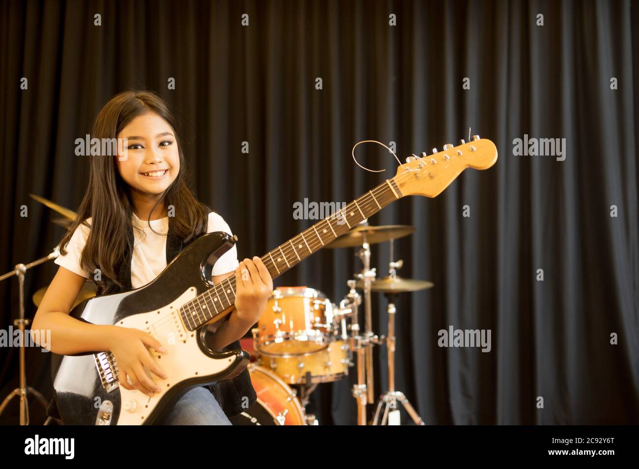 A portrait of a cute Asian girl with long hair playing an electric ...