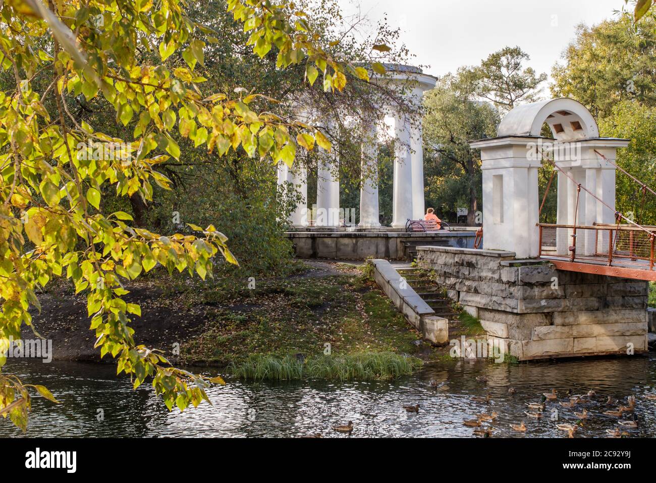 Old park in the fall. View through the branches of a white rotunda and ...