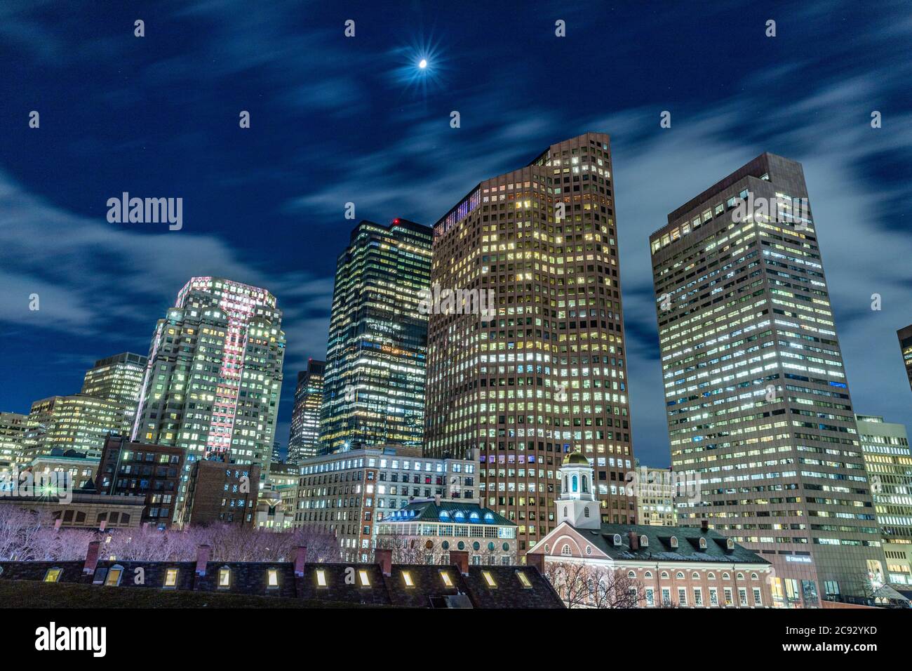 Clouds stretching over city buildings at night with the moon shining ...