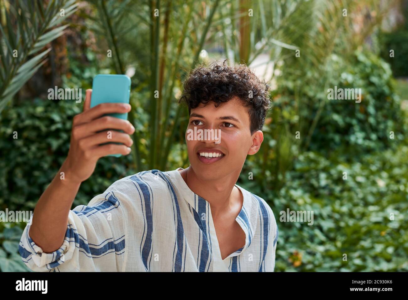 A young man with afro hair is doing a self-portrait in a park Stock ...
