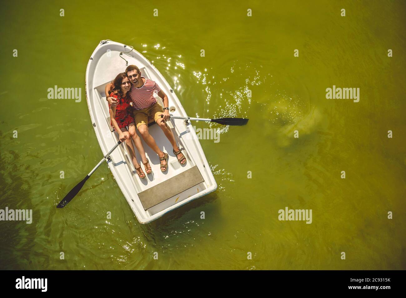 Top view of happy loving couple rowing a small boat on a lake. A fun ...