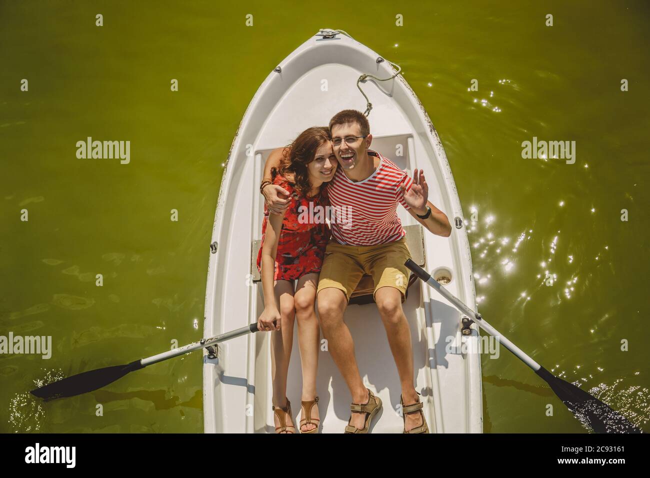 Top view of happy loving couple rowing a small boat on a lake. A fun ...