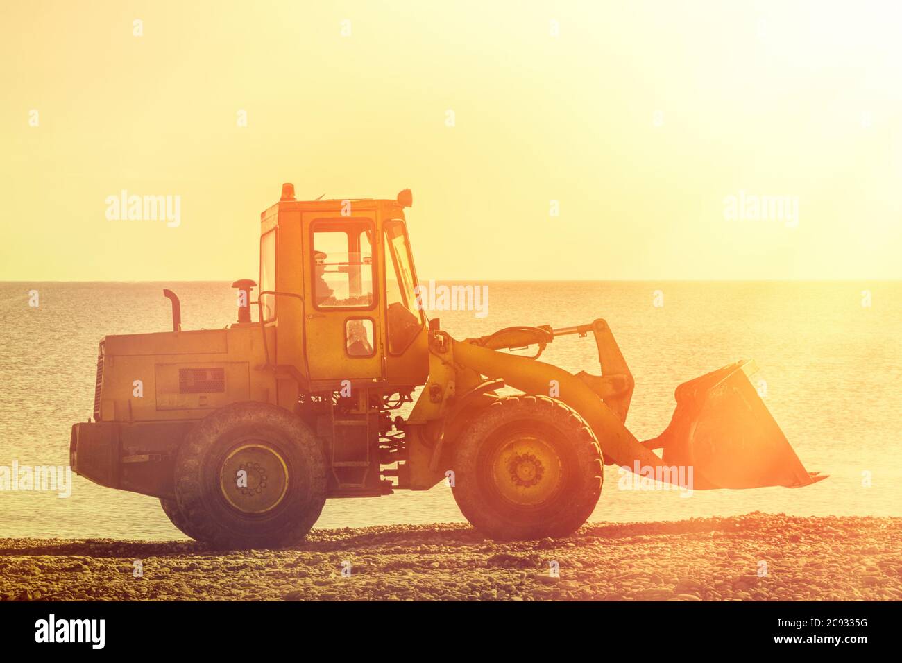 Bulldozer rides on the beach. In the background sea and sky. Tint Stock ...