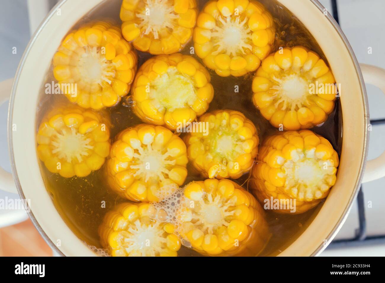 the process of making sweet corn in a pot on the gas stove at home ...