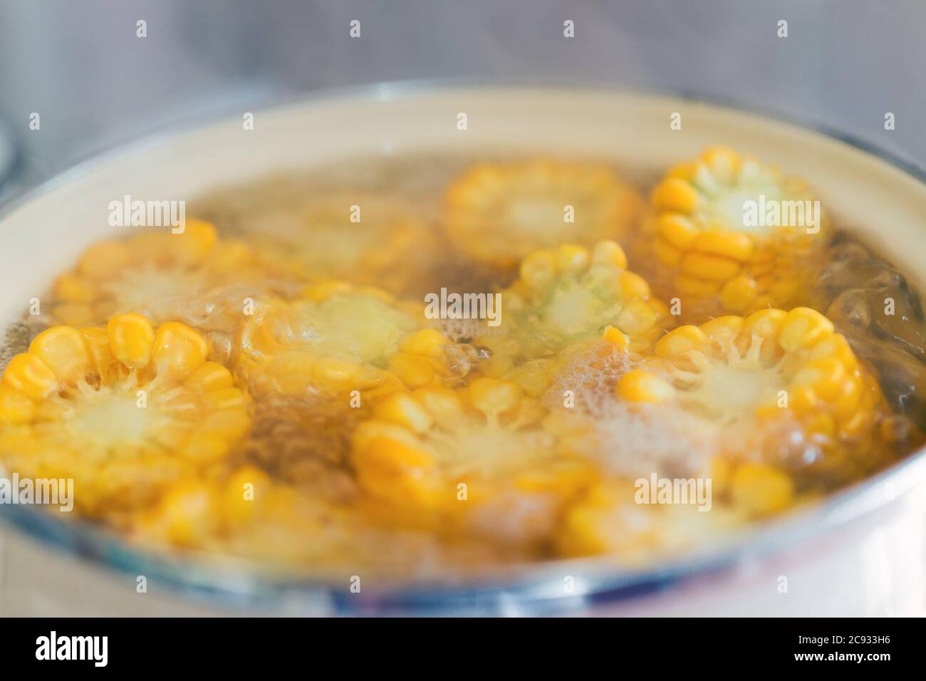 the process of making sweet corn in a pot on the gas stove at home ...