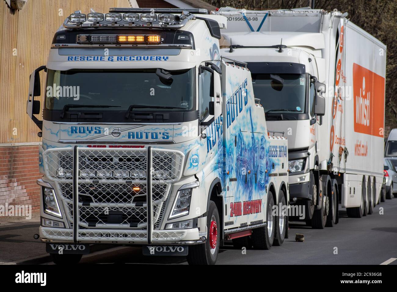 Volvo wrecker recovering a broken down HGV on a narrow urban street ...
