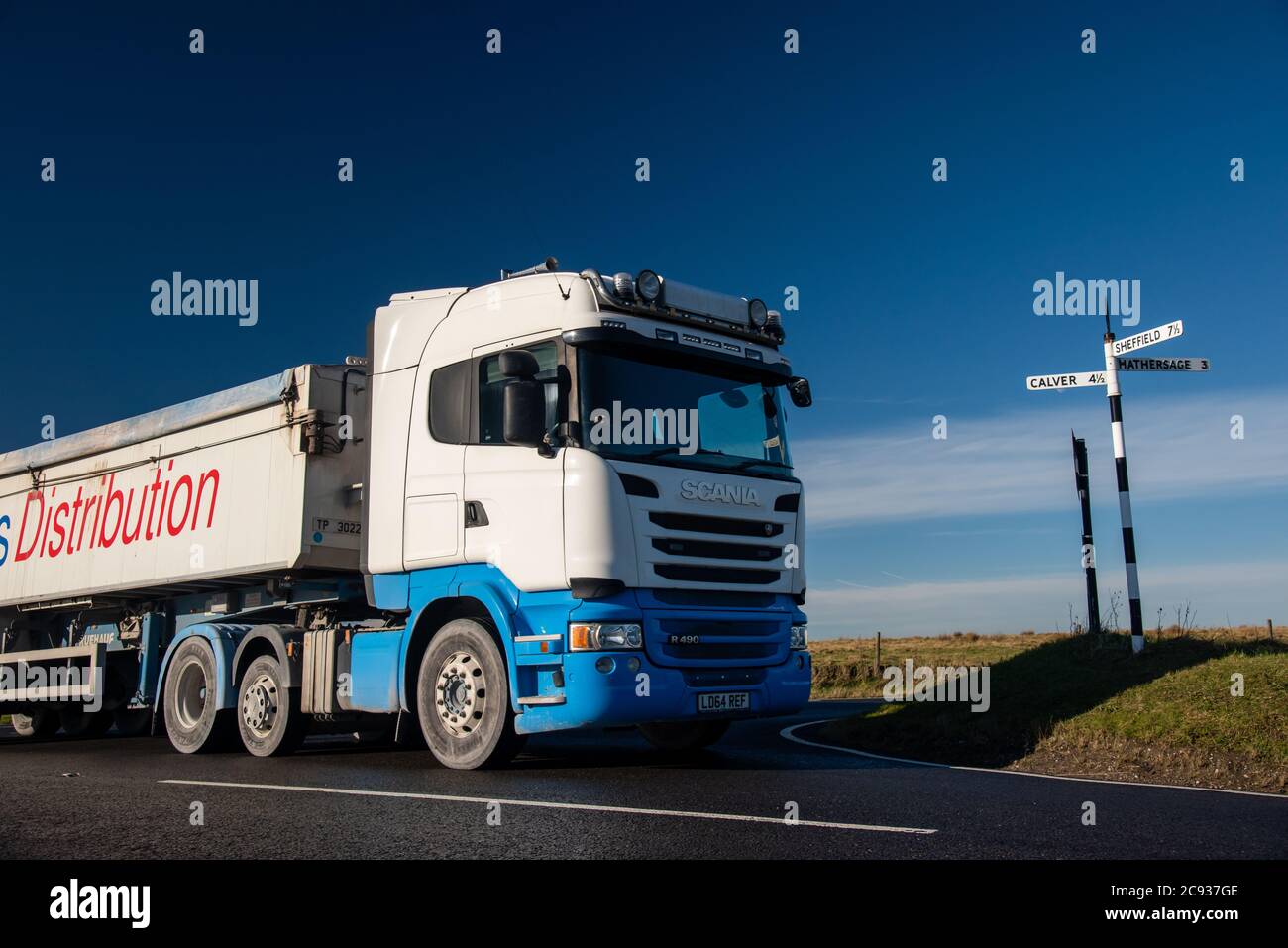 Lomas Distribution Scania bulk tipper driving past an old road sign in ...