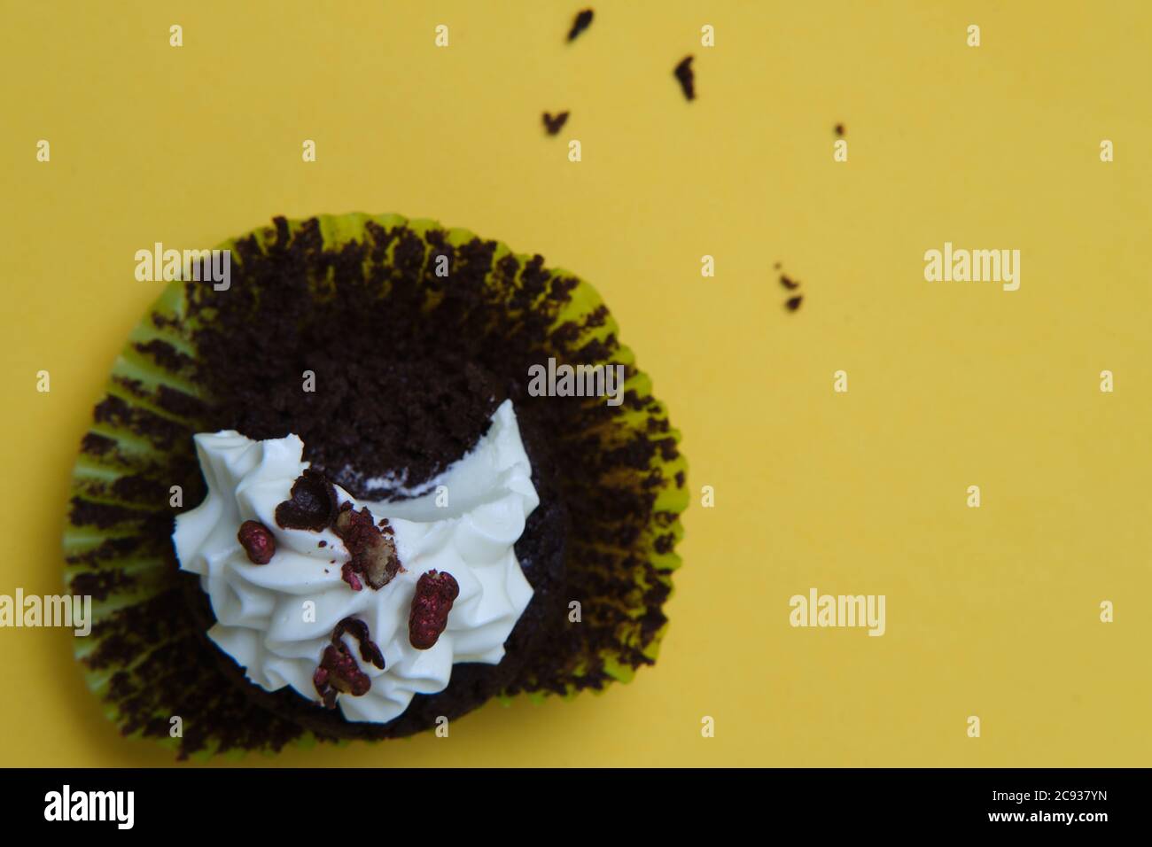 Crumbs and cream of a bitten cupcake on a yellow background Stock Photo ...