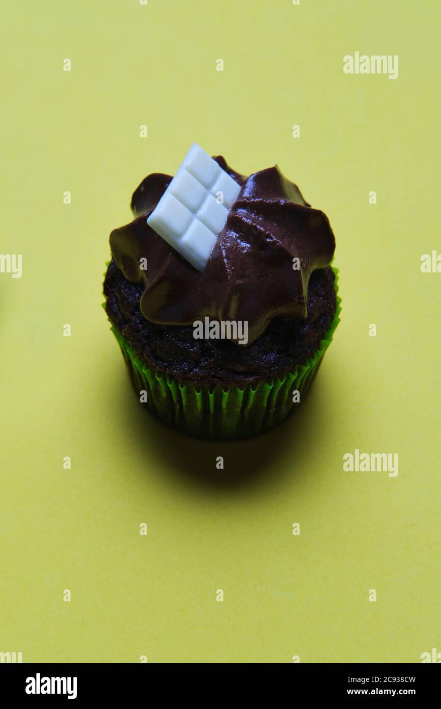 Vertical closeup shot of a chocolate cupcake on a green background ...