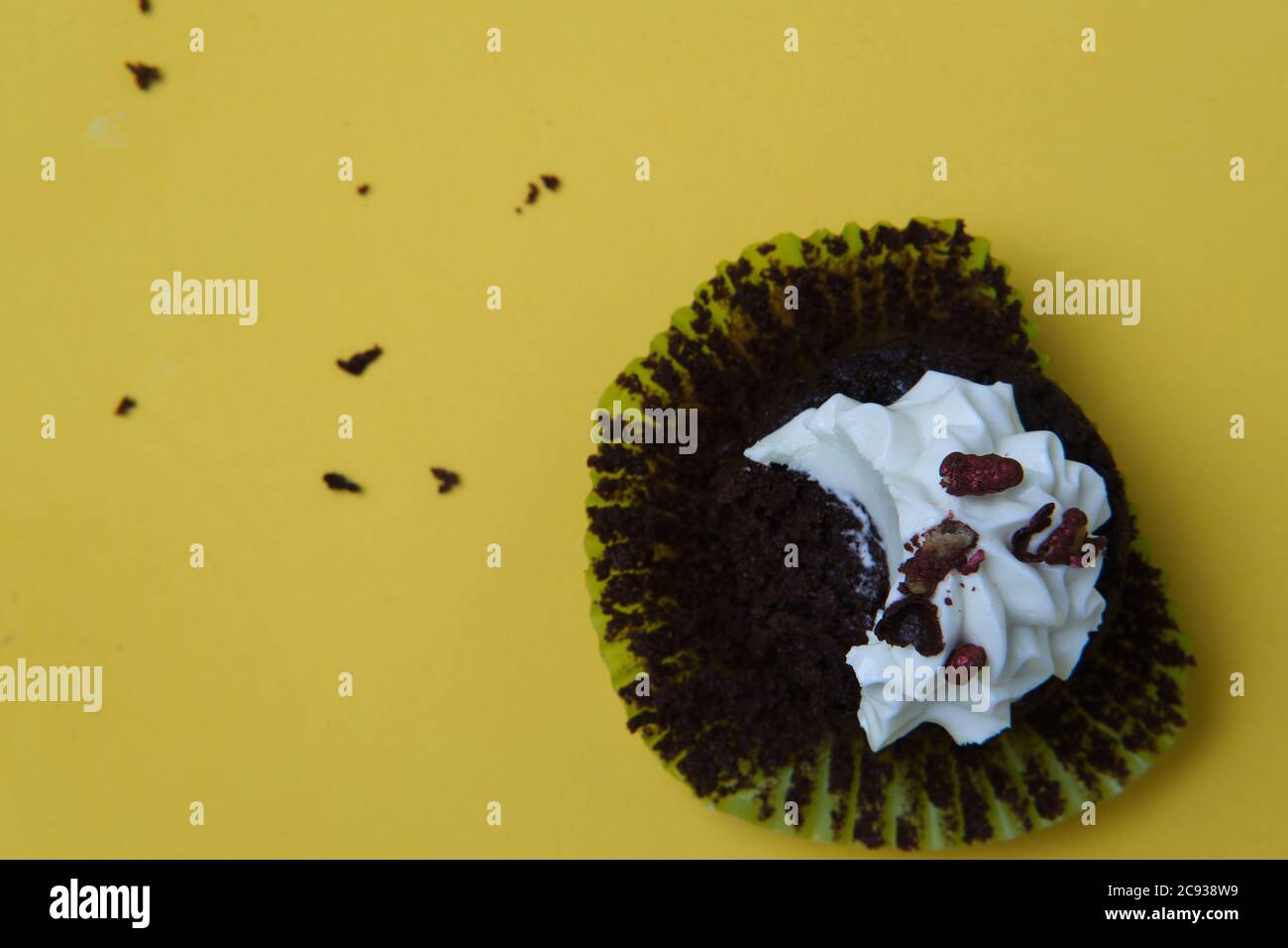 Crumbs and cream of a bitten cupcake on a yellow background Stock Photo ...