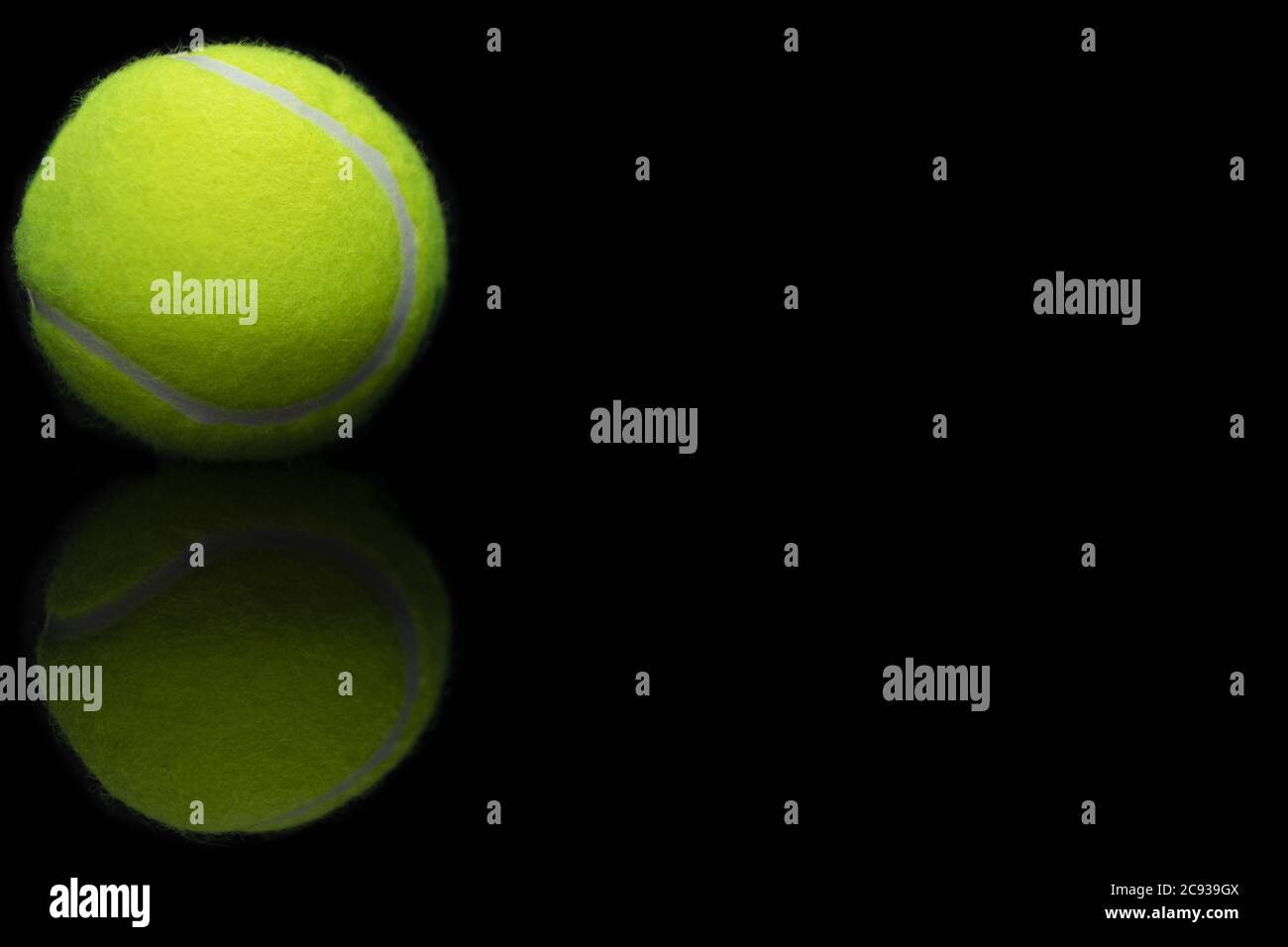 Closeup shot of the reflection of a tennis ball on a reflective black ...