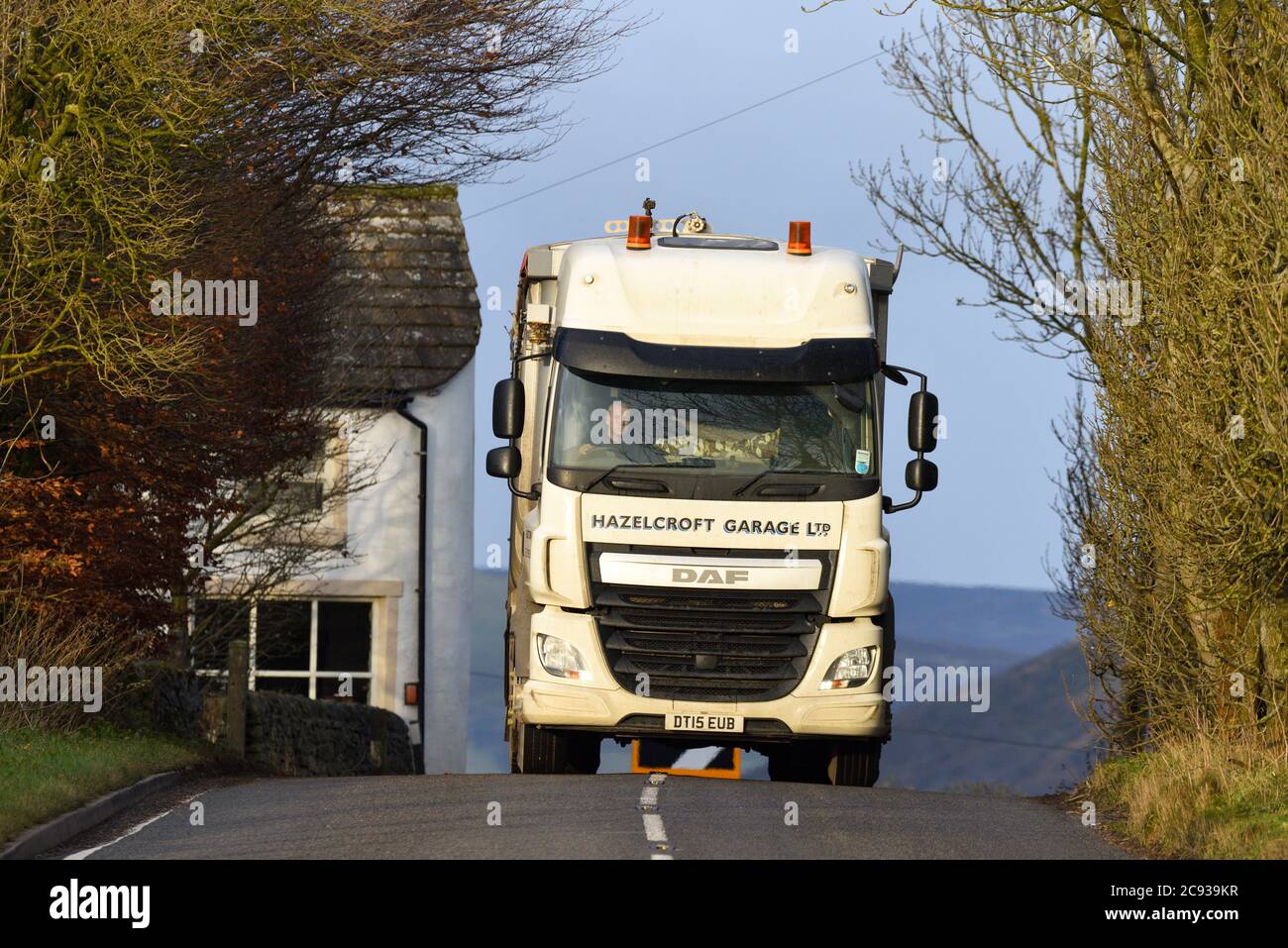 A DAF XF pulling a bulk tipper trailer, driving along a narrow road in ...