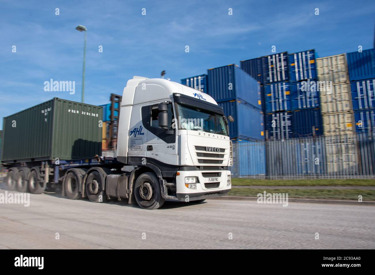 Iveco truck pulling a container trailer passing a container park on an ...