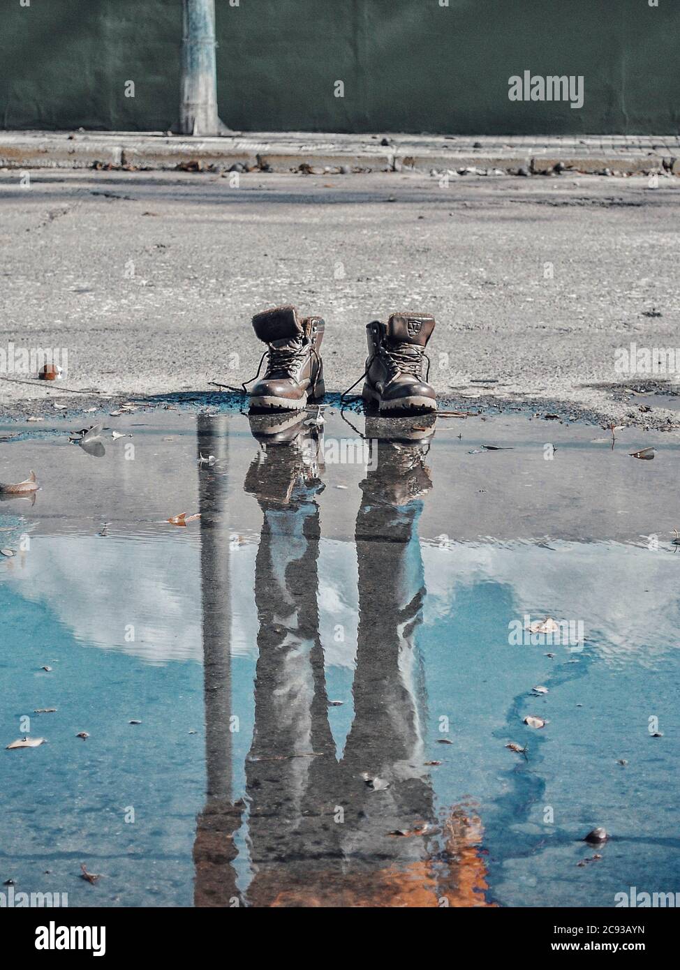 Pair of boots in a puddle of water with a person wearing them in the ...