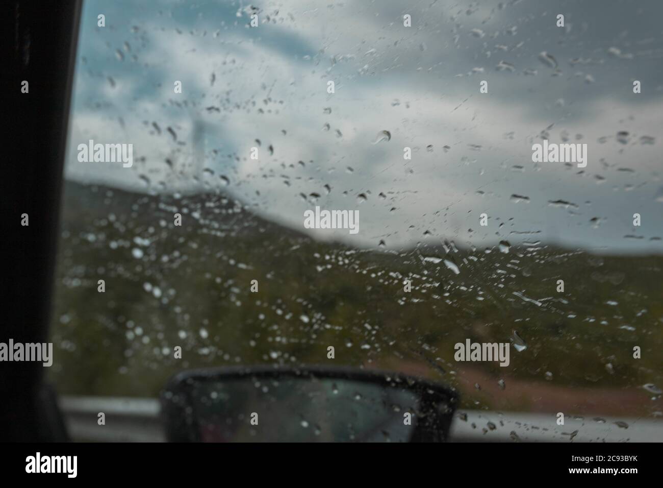 Cloudy and gloomy sky seen through the wet glass window of the car ...