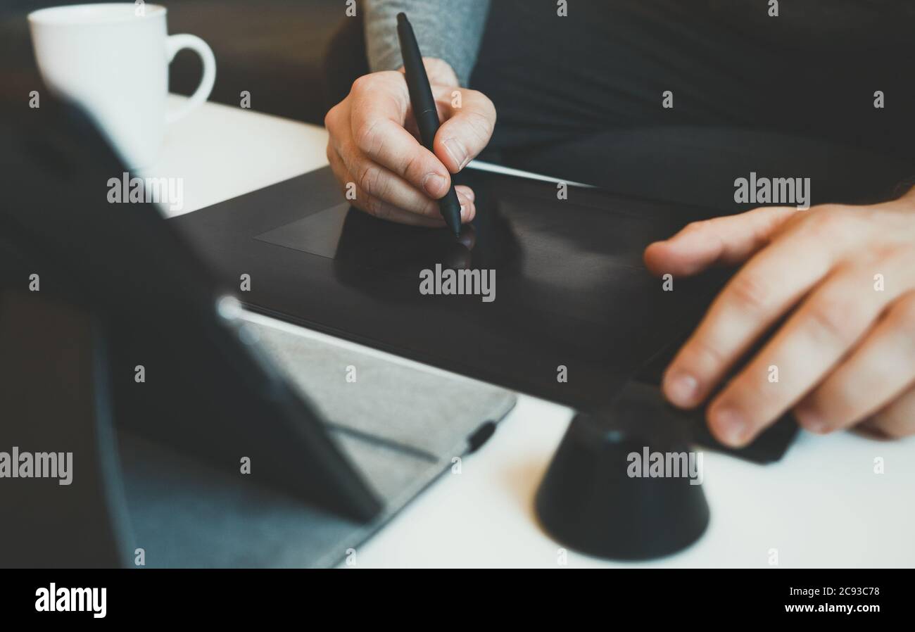 Graphic designer using electronic drawing tablet at home Stock Photo ...
