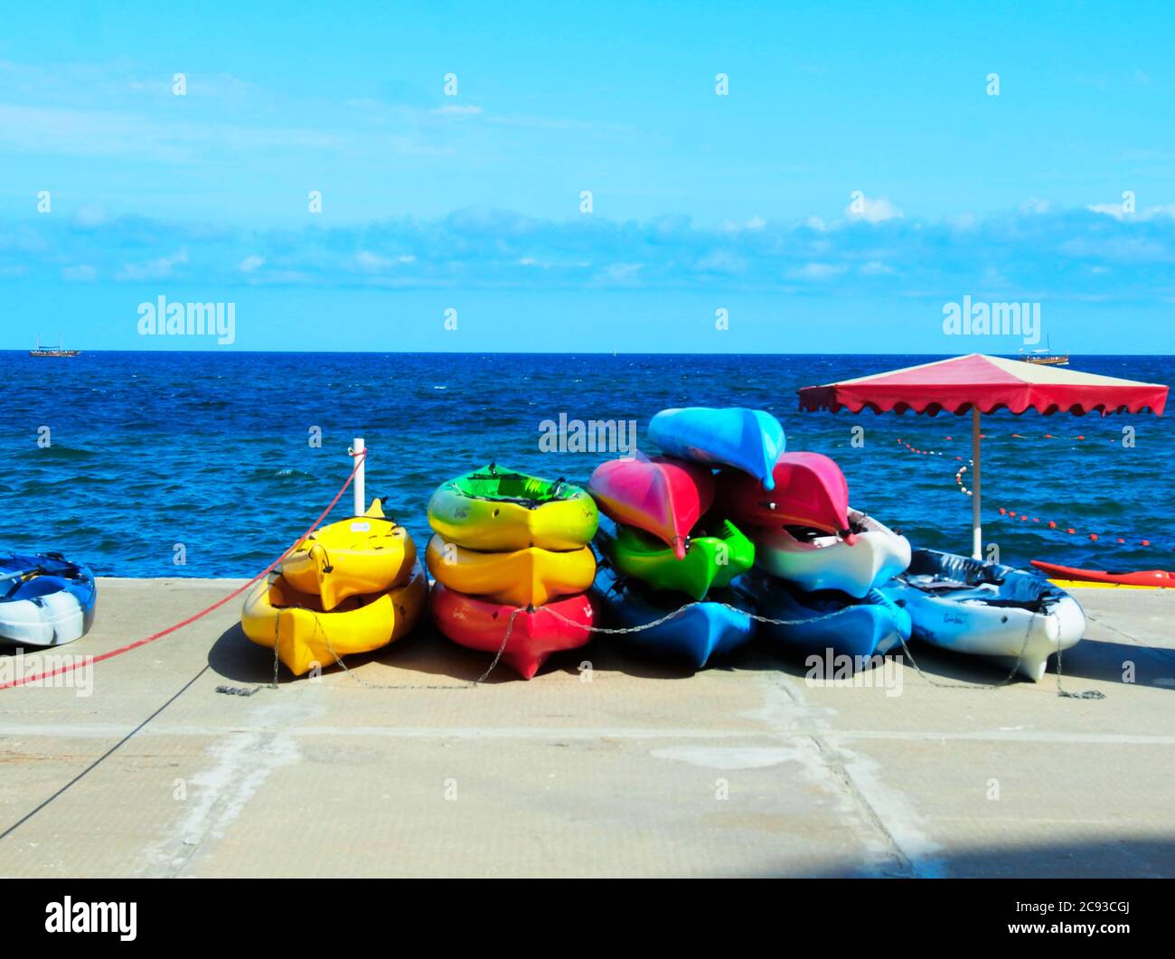 Stack of brightly colored canoes by the sea Stock Photo - Alamy