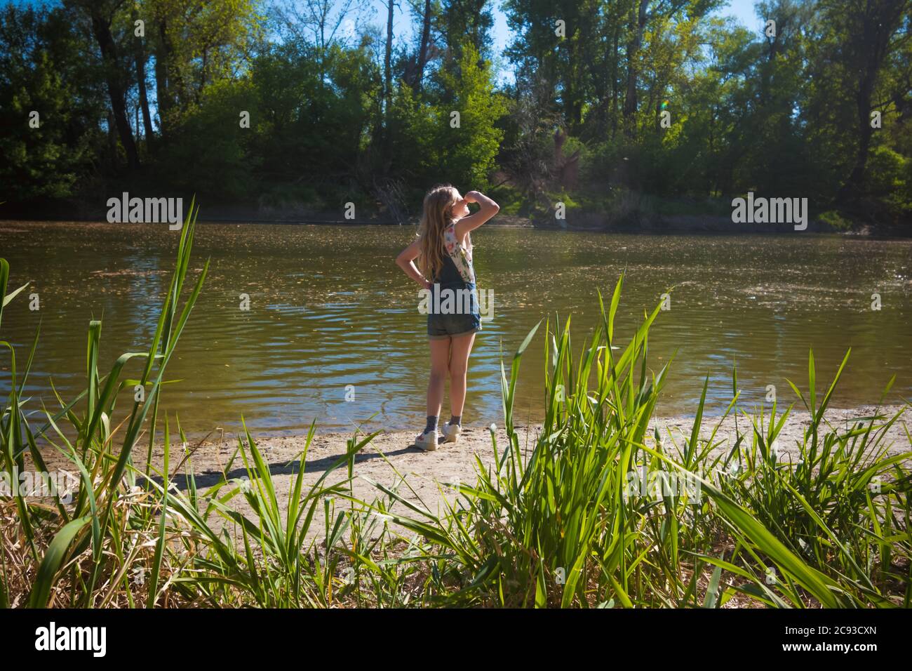 cute girl with long hair back view standing in the river shore relaxing ...