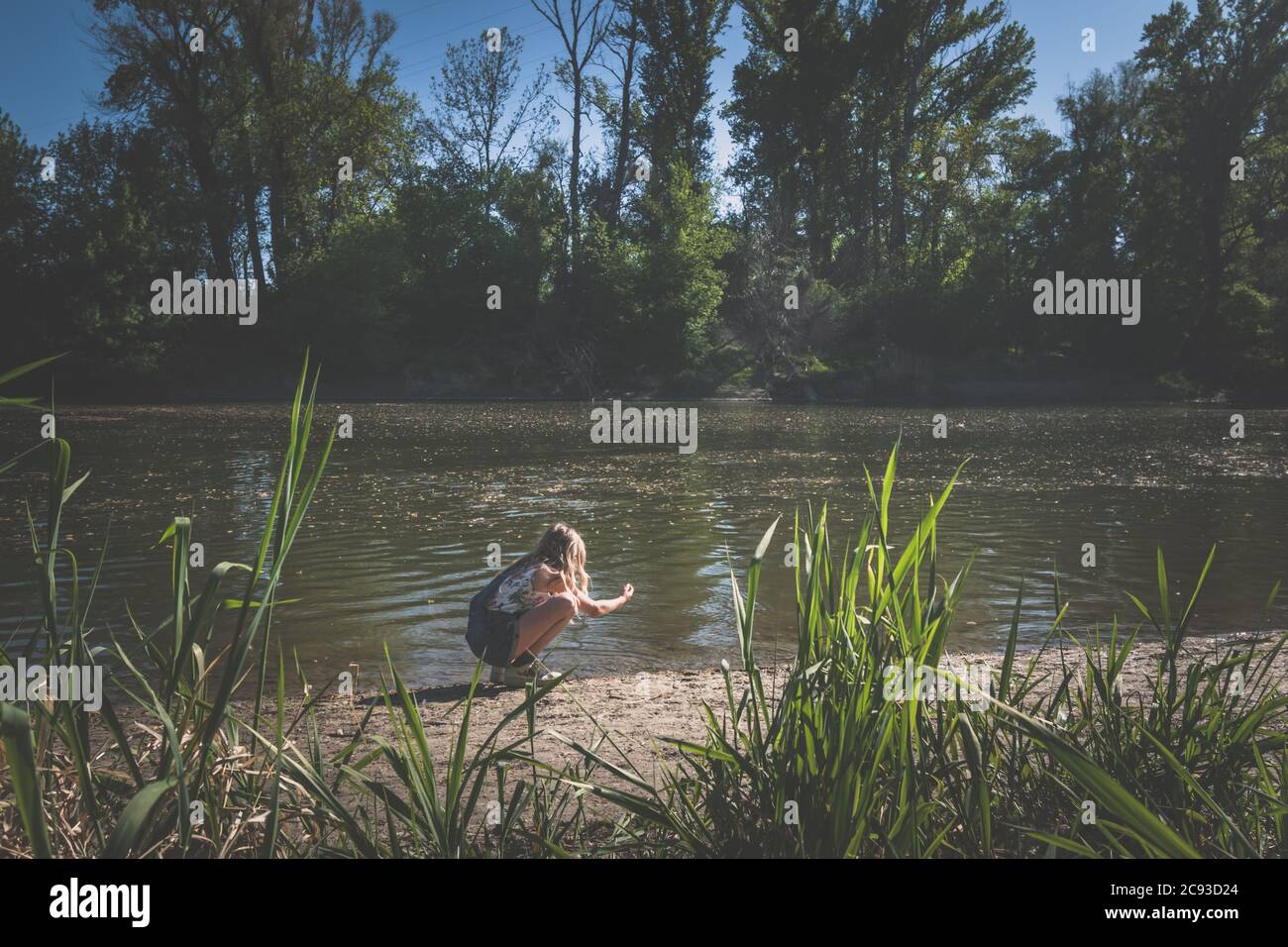 cute girl with long hair back view in the river shore relaxing in green ...