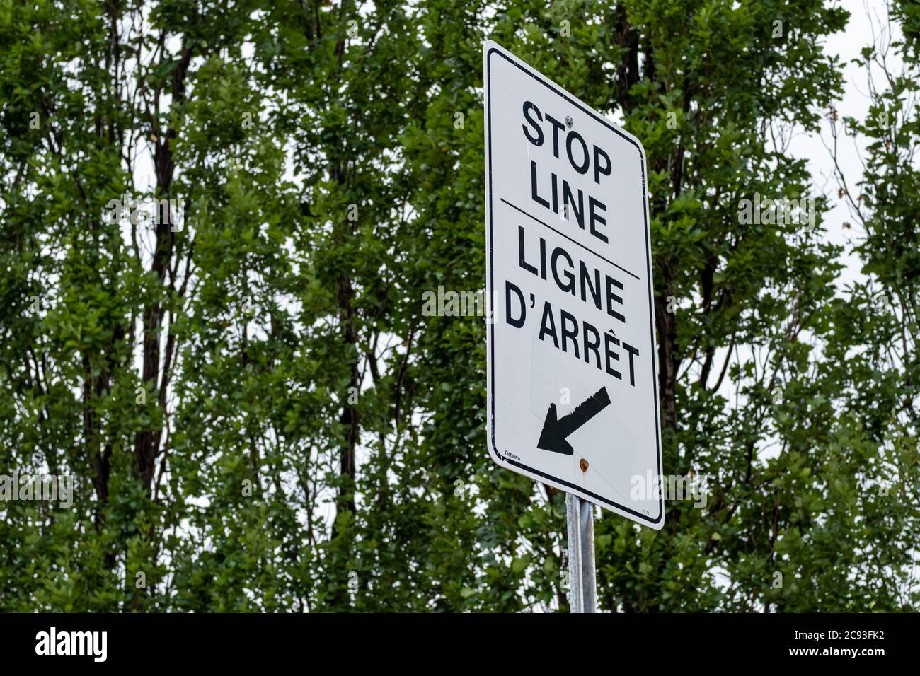 A bilingual sign indicates the location of a stop line for a traffic ...