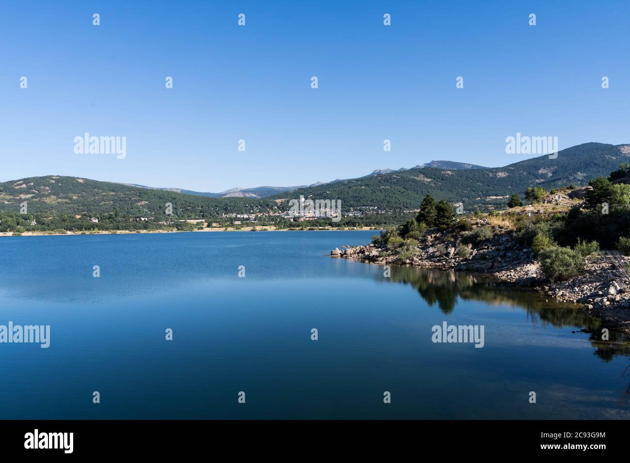 The shore of a water reservoir surrounded by green mountains in ...