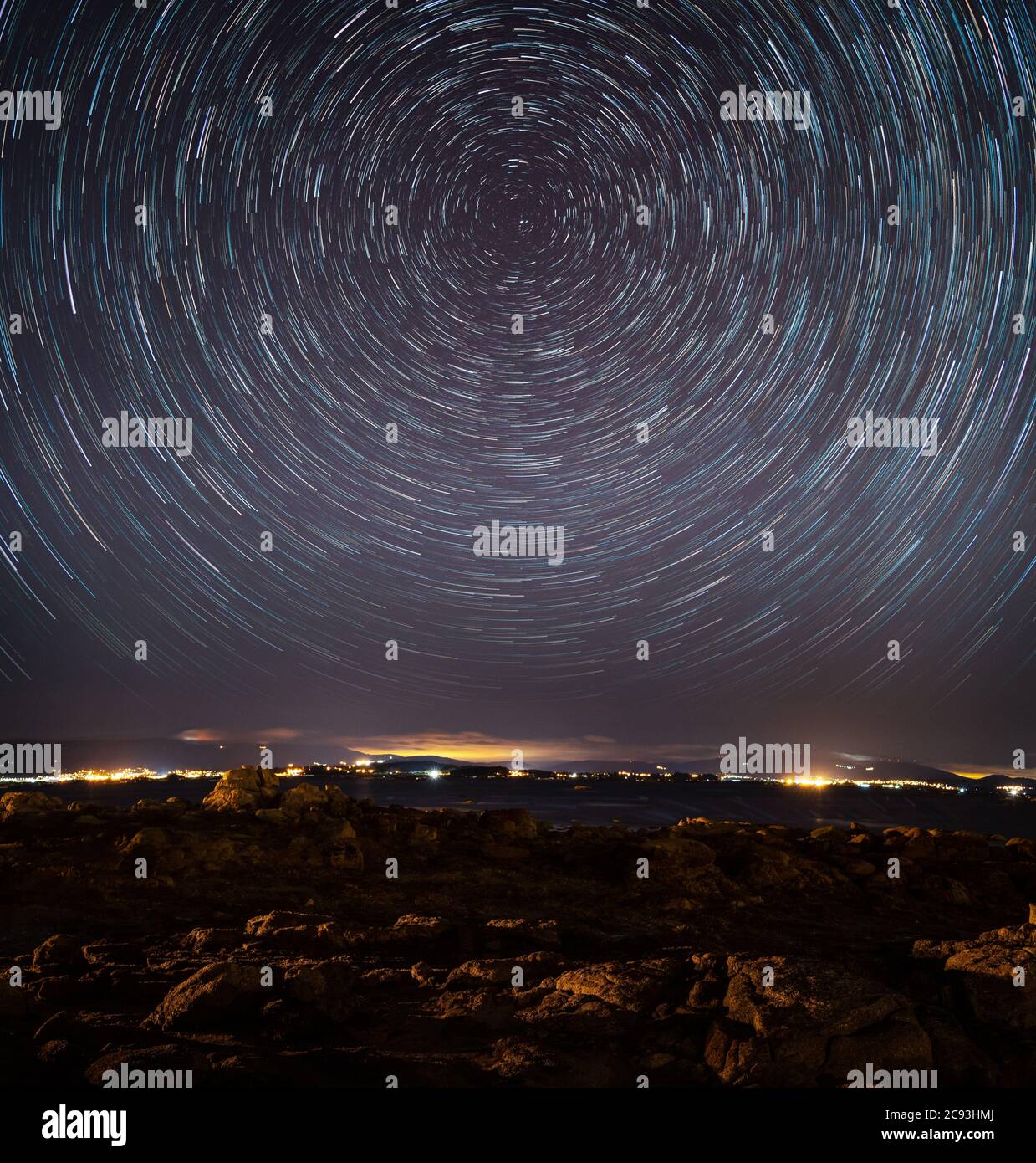 Town surrounded by lights in the evening under a starry sky with long ...