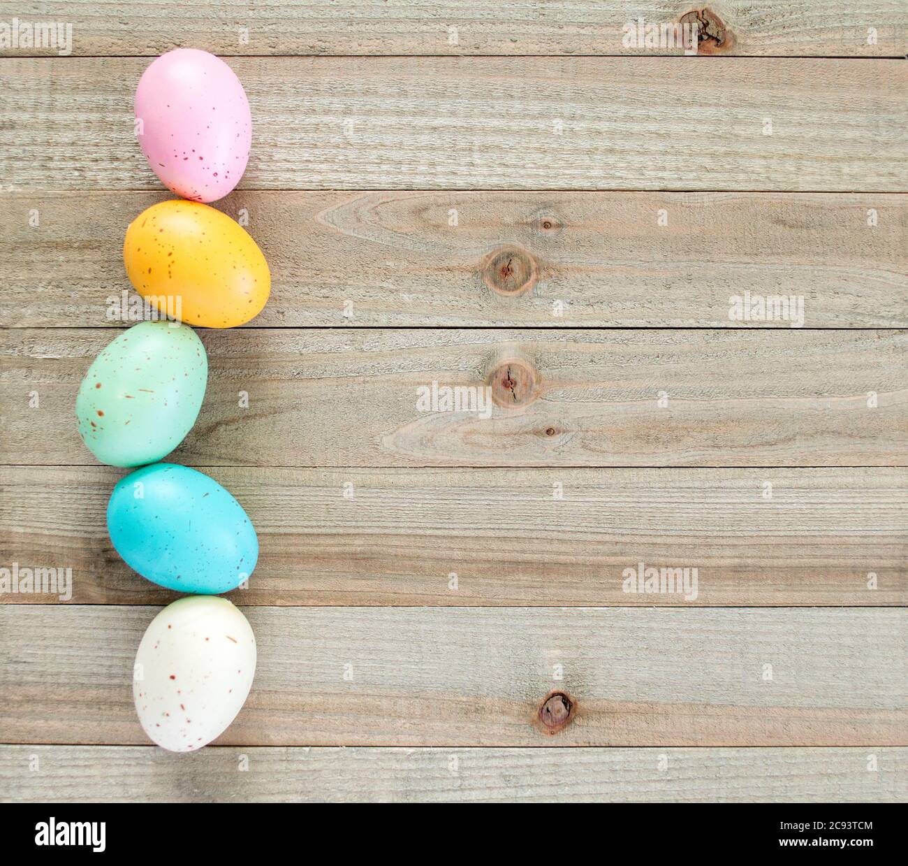 a vertical border of colorful speckled Easter eggs on a wood background ...