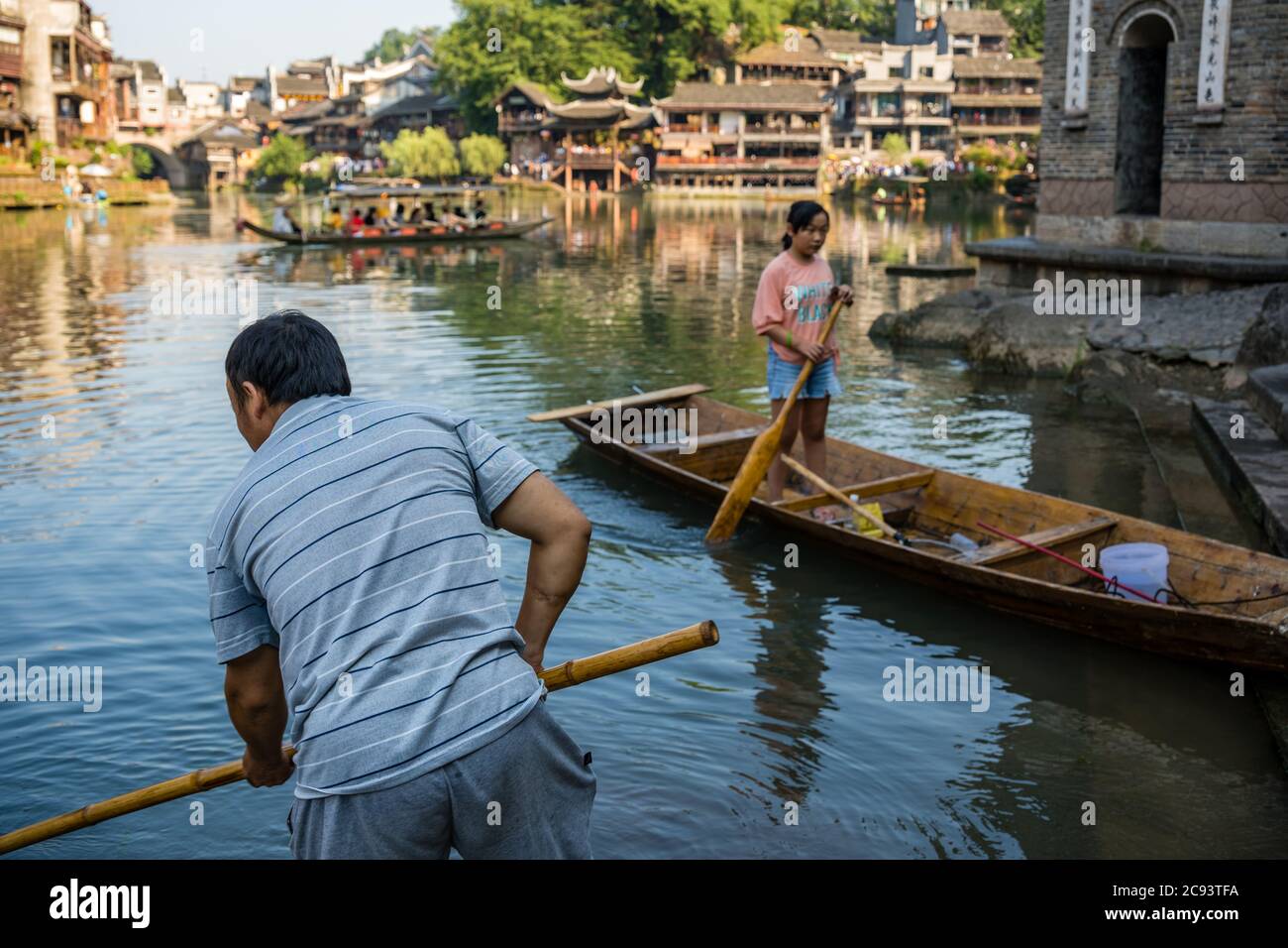 Feng Huang, China - August 2019 : Man with a long pole directing old ...
