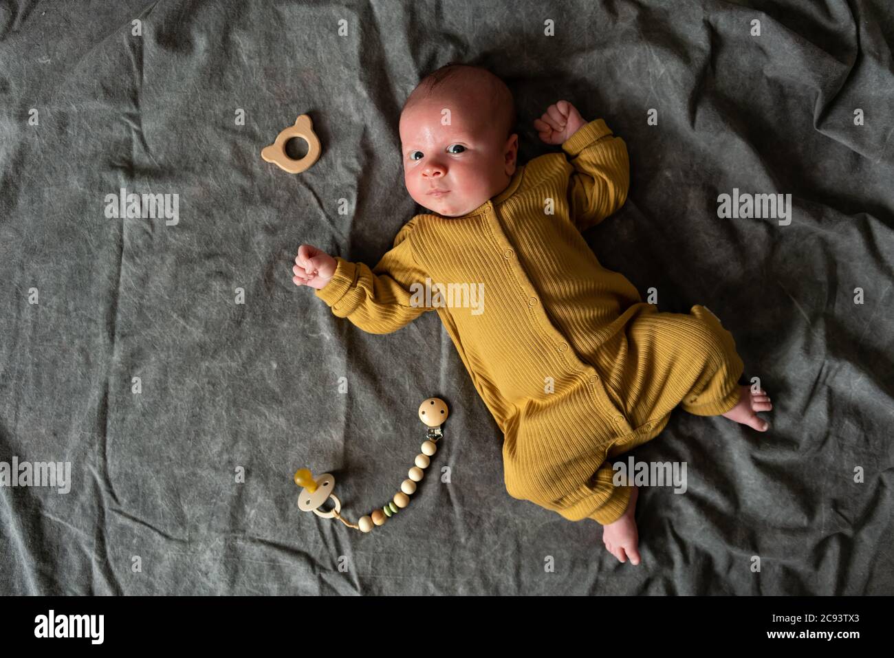 One month newborn baby with open eyes lies on his back on grey ...