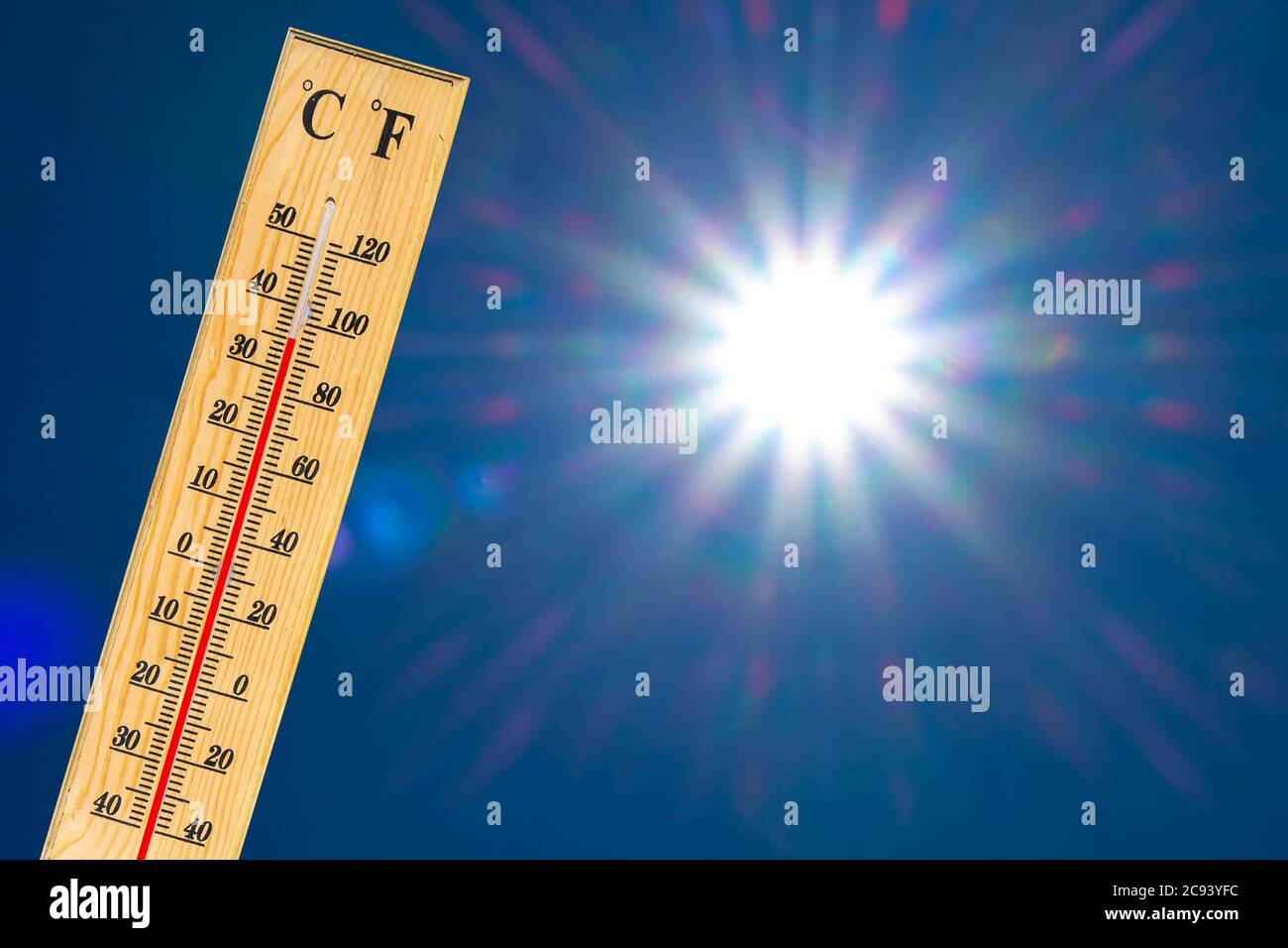 Wooden weather thermometer measurement on a blue sky with the sun on a ...