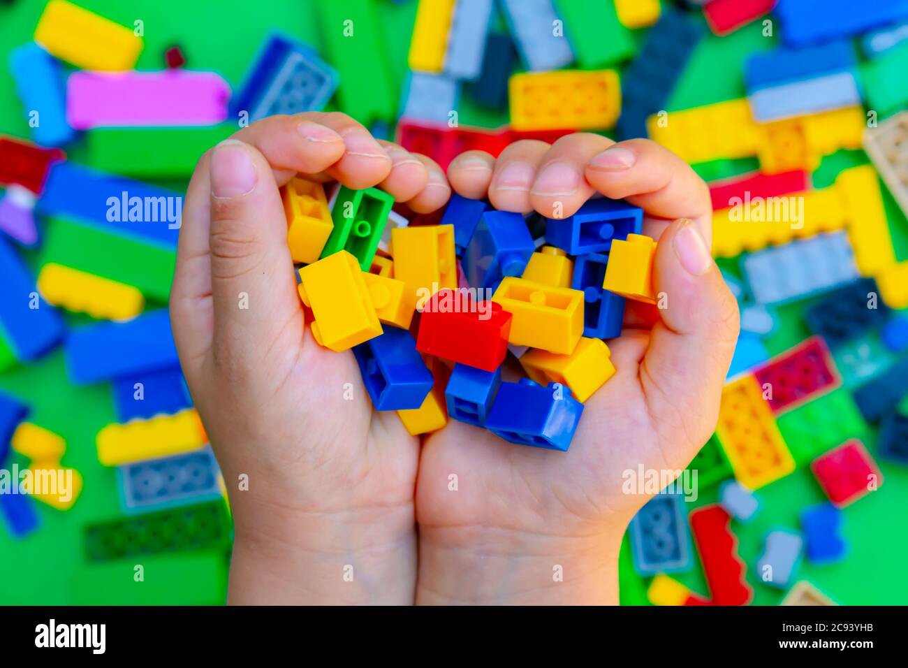A kid holding small pieces of interlocking plastic colorful bricks toy ...